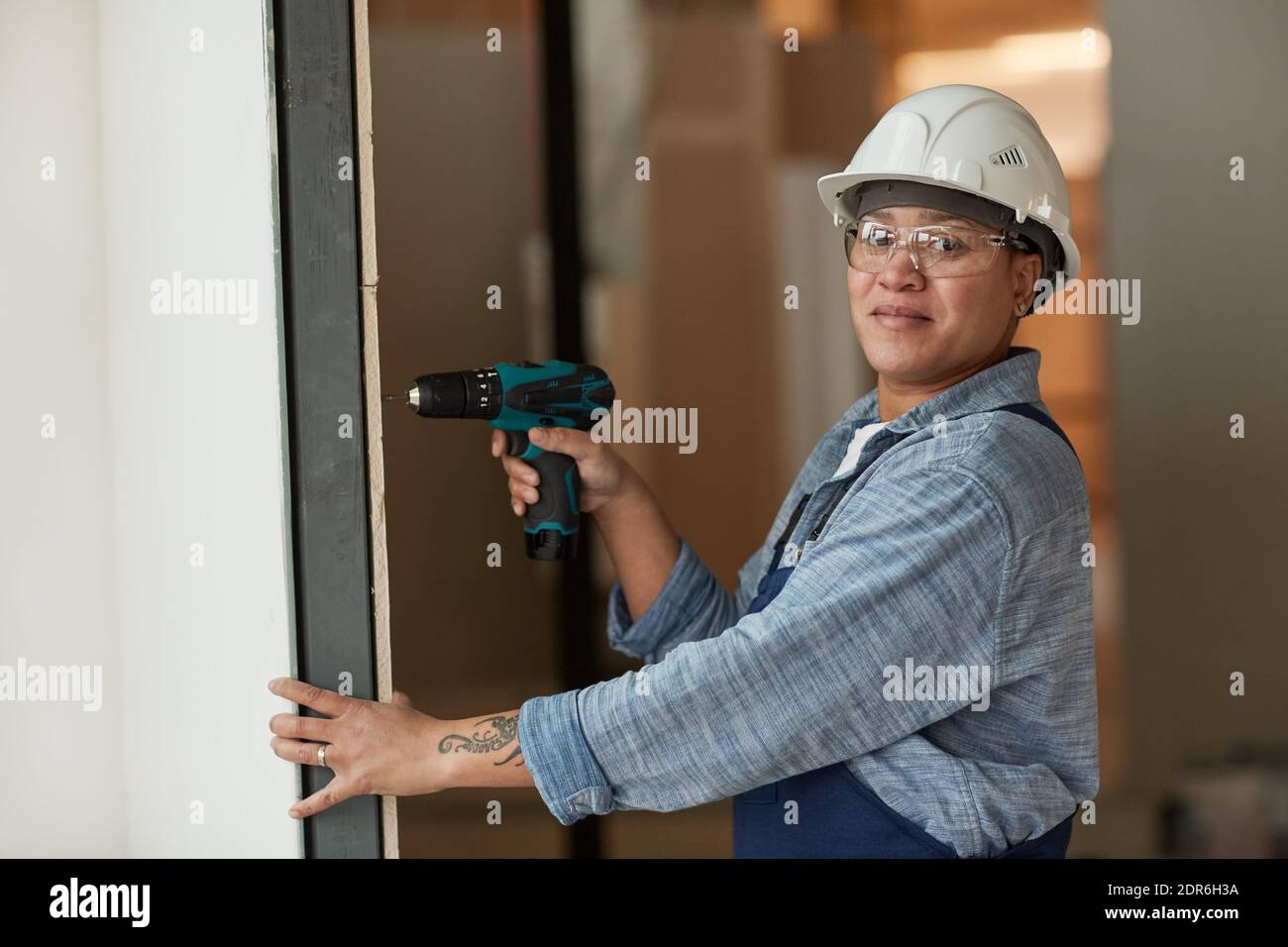Waist up portrait of modern female worker smiling at camera while ...