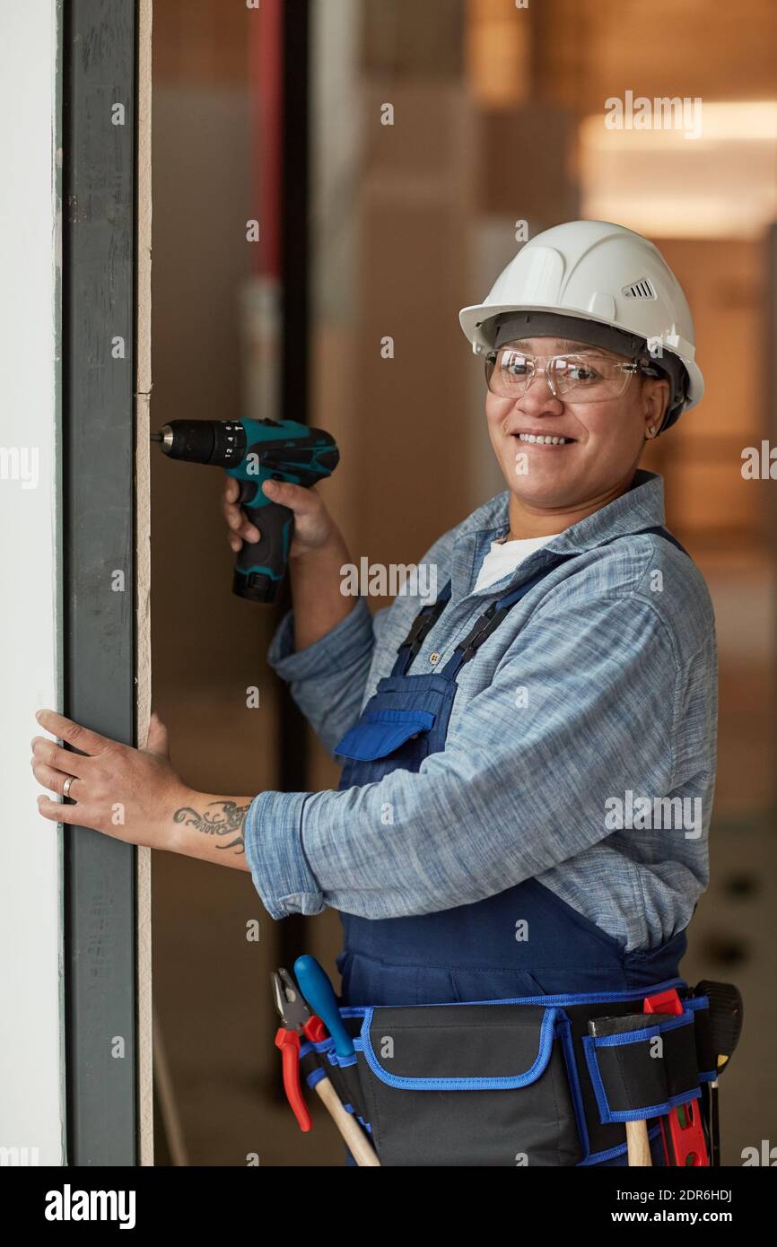 Vertical portrait of modern female worker smiling at camera while ...