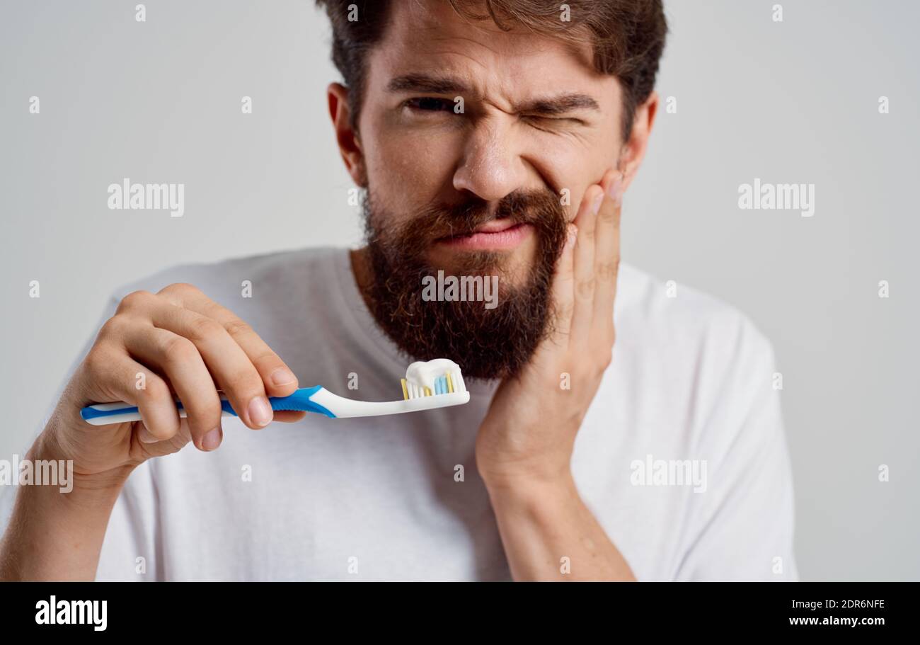 a man with a toothbrush gestures with his hands pain in the oral cavity ...