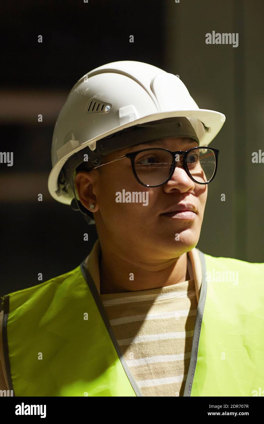 Shadow and light portrait of modern female engineer wearing hardhat and ...