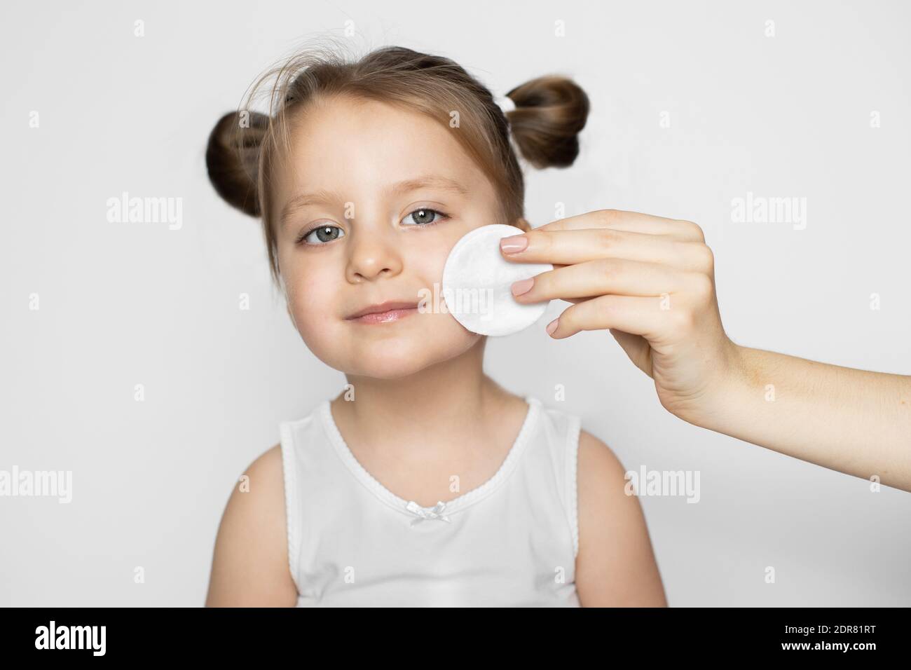 Close up of mom's hand, cleaning face of little 3 year old girl with a ...