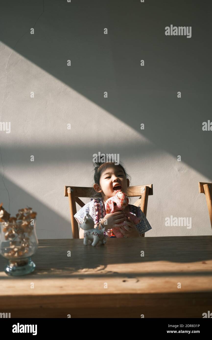 Cute Girl Sitting On Table At Home Stock Photo - Alamy