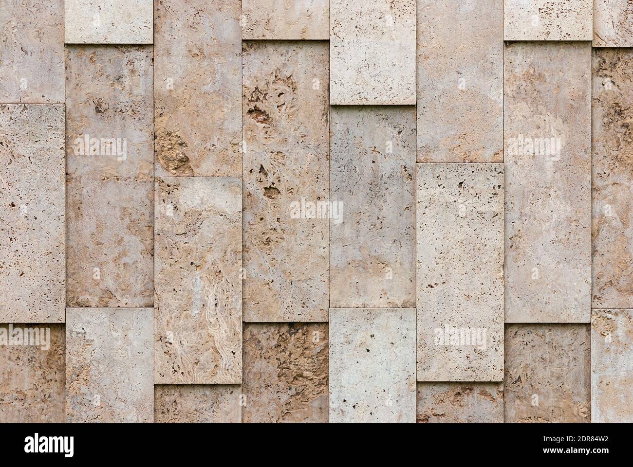 beige-gray wall of natural textured stone blocks, irregularly arranged ...