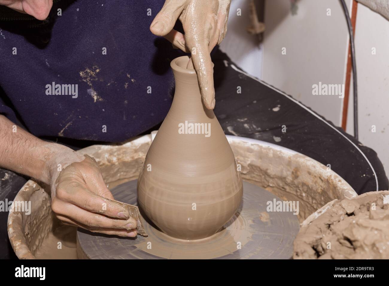 Pottery - skilled wet hands of potter shaping the clay of a vase on ...