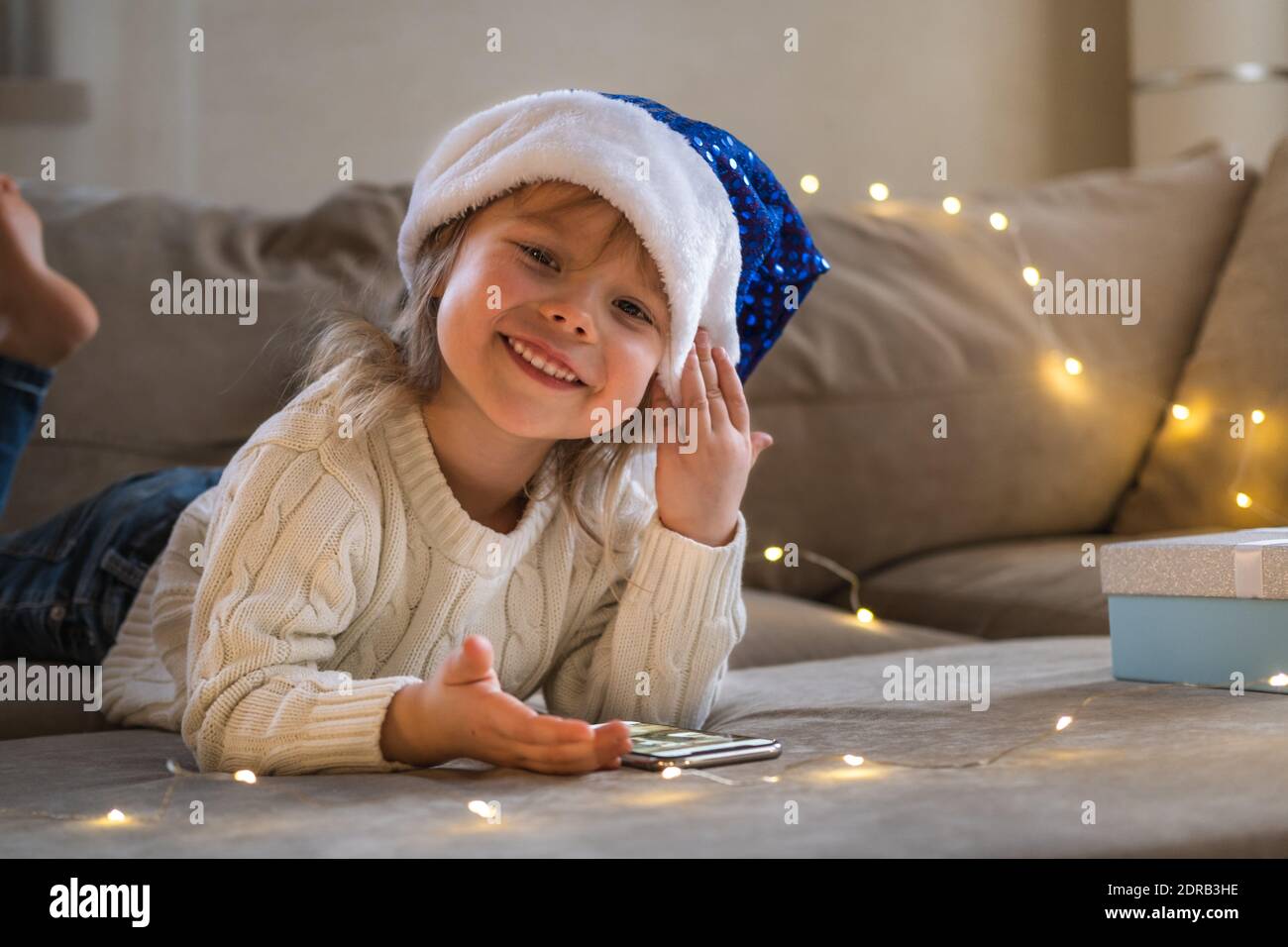Portrait of girl in blue Santa hat using mobile phone for video call ...