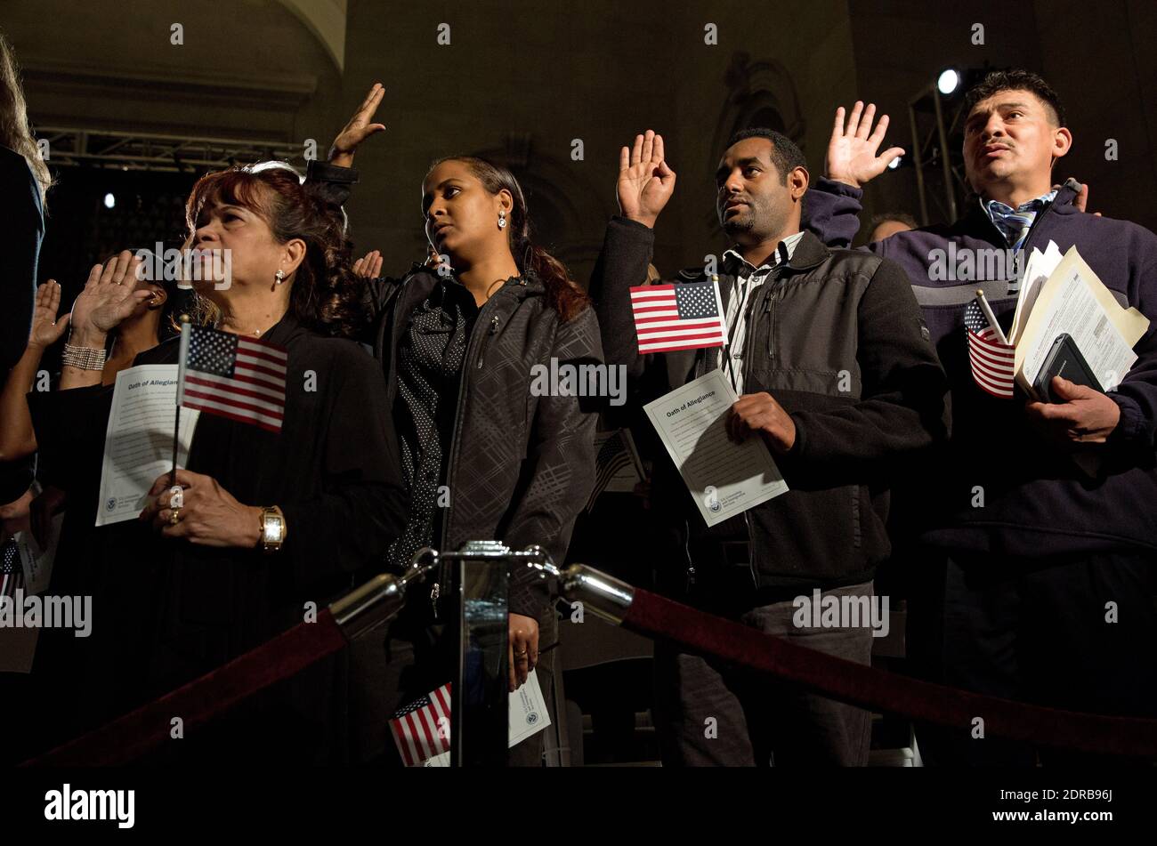 Naturalization candidates raise their hands and pledge the Oath of ...