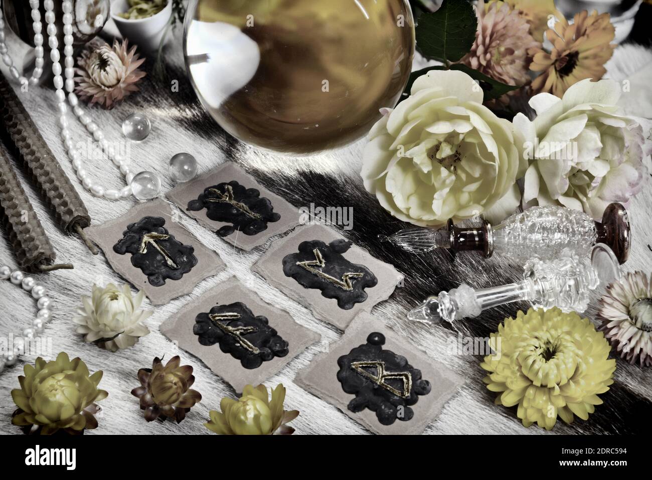 Styled still life with black runes, magic ball, yellow flowers, candles ...