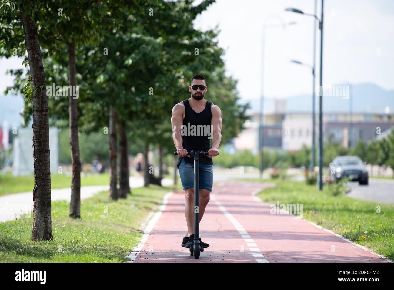 Young Attractive Athlete Is Driving His Scooter on the Street at Bright ...