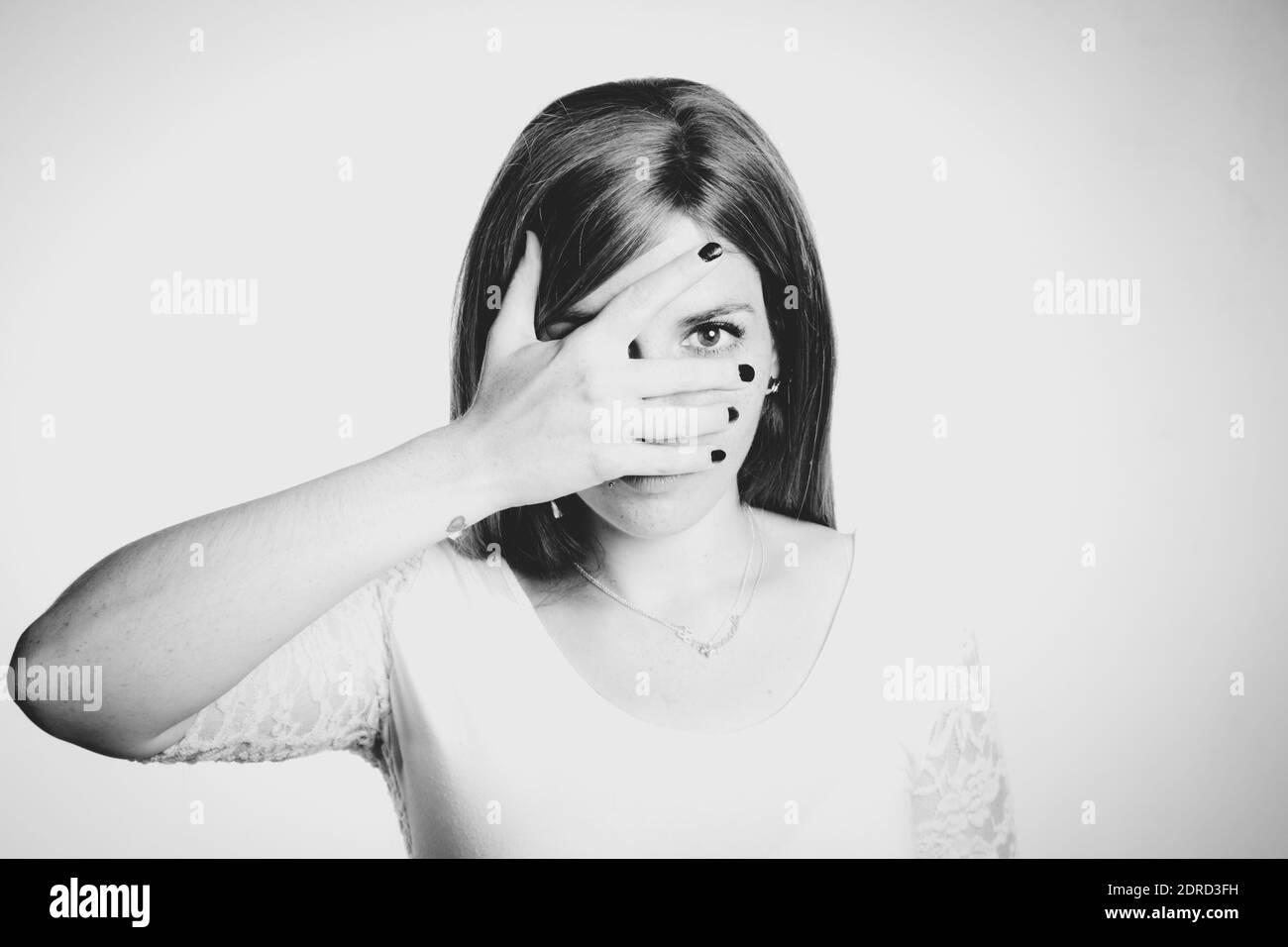 Close Up Portrait Of Young Woman Covering Face Against White Background