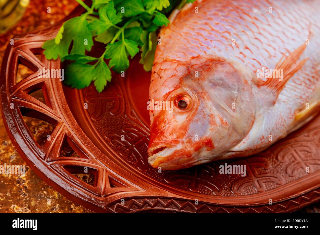 Pink tilapia fish with herbs and lemon on tray. Close up Stock Photo ...