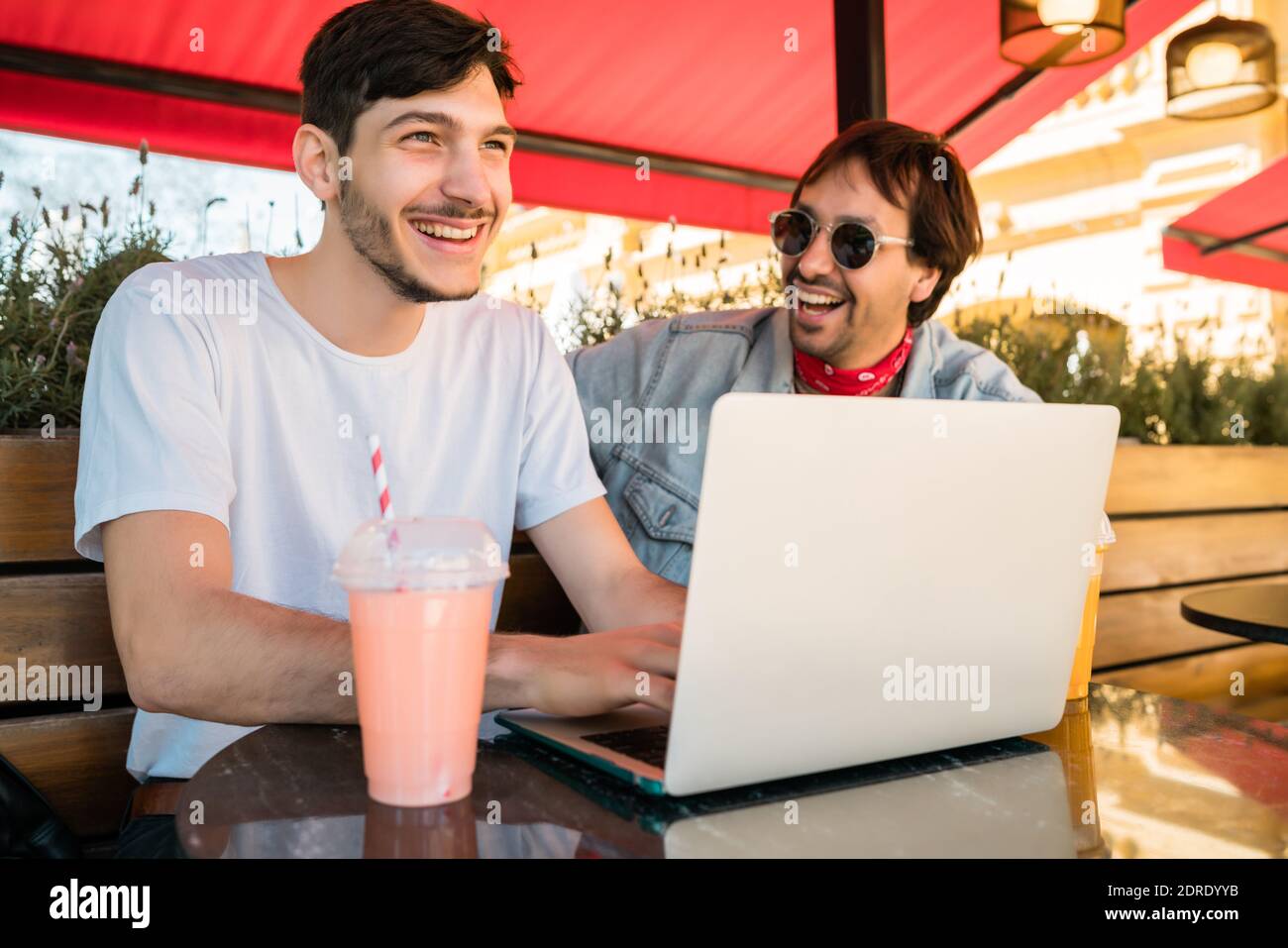 Two young friends using laptop at coffee shop Stock Photo - Alamy
