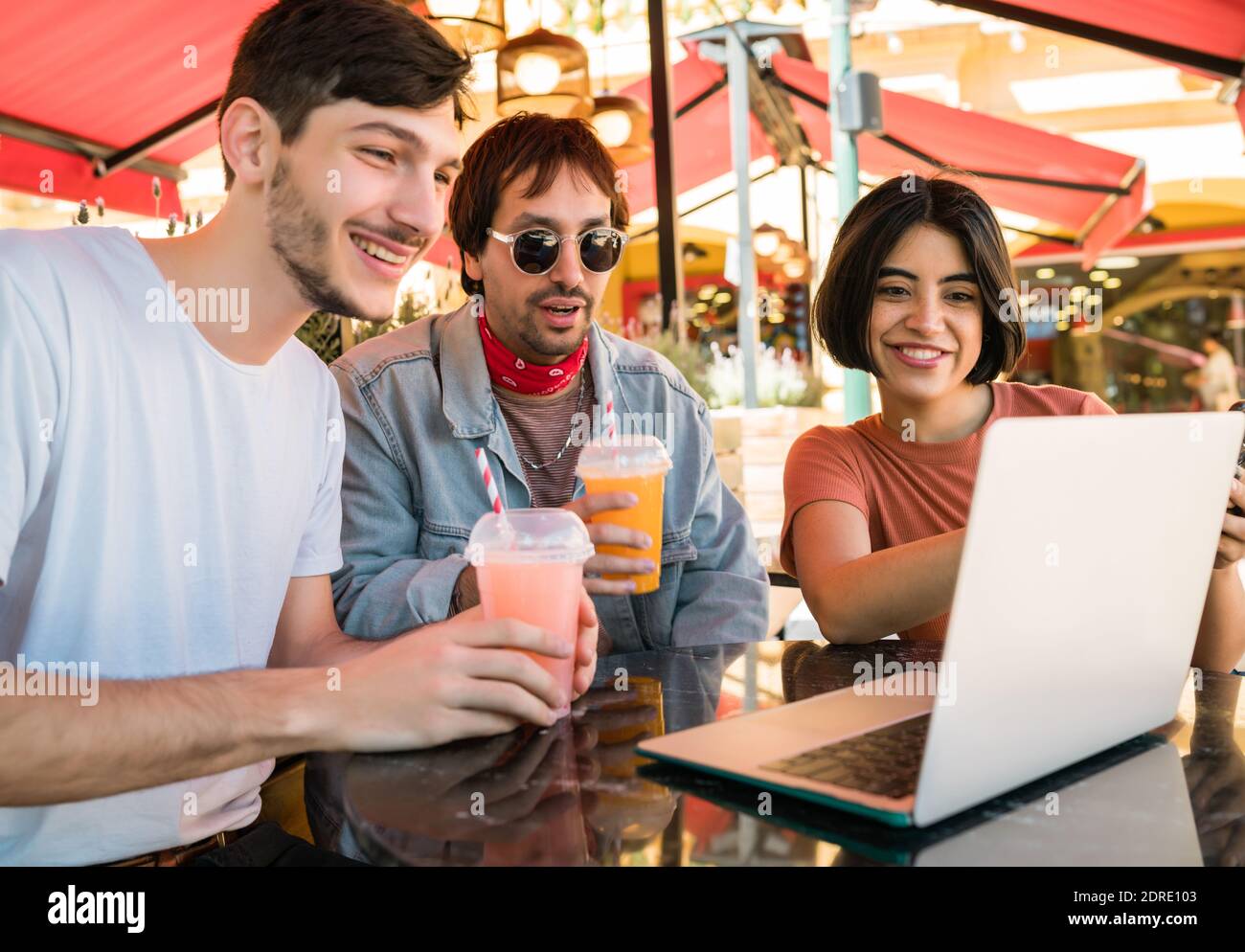 Three young friends using laptop at coffee shop Stock Photo - Alamy