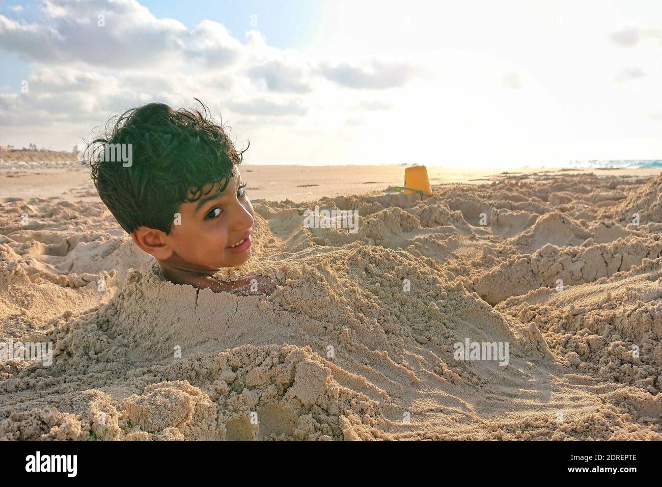 Boy buried in sand on hi-res stock photography and images - Alamy
