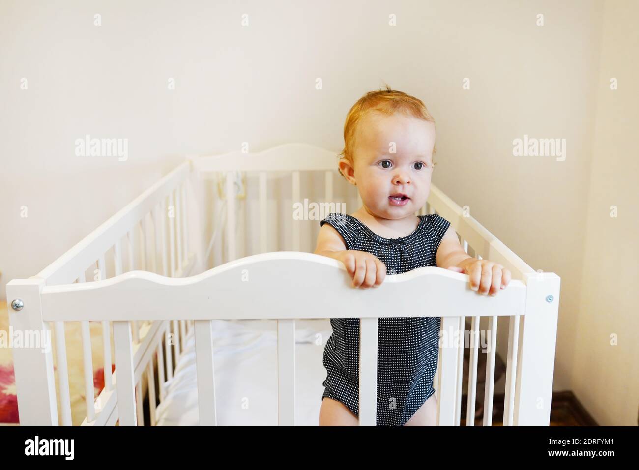 Beautiful baby standing in crib. Portrait of cute baby girl stand in ...