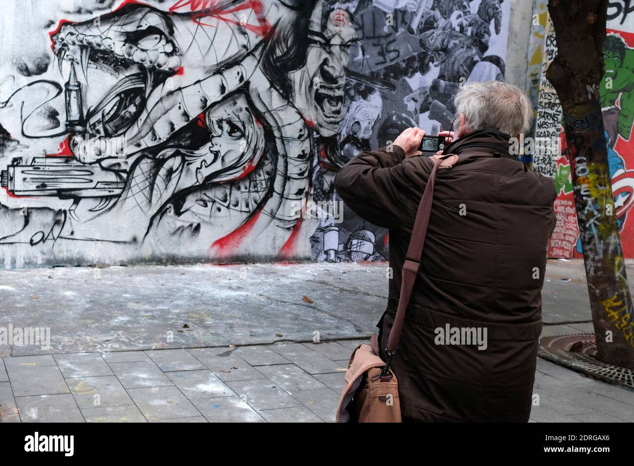 A man takes a photo of a grafitti by artist Lask is seen on a big mural ...