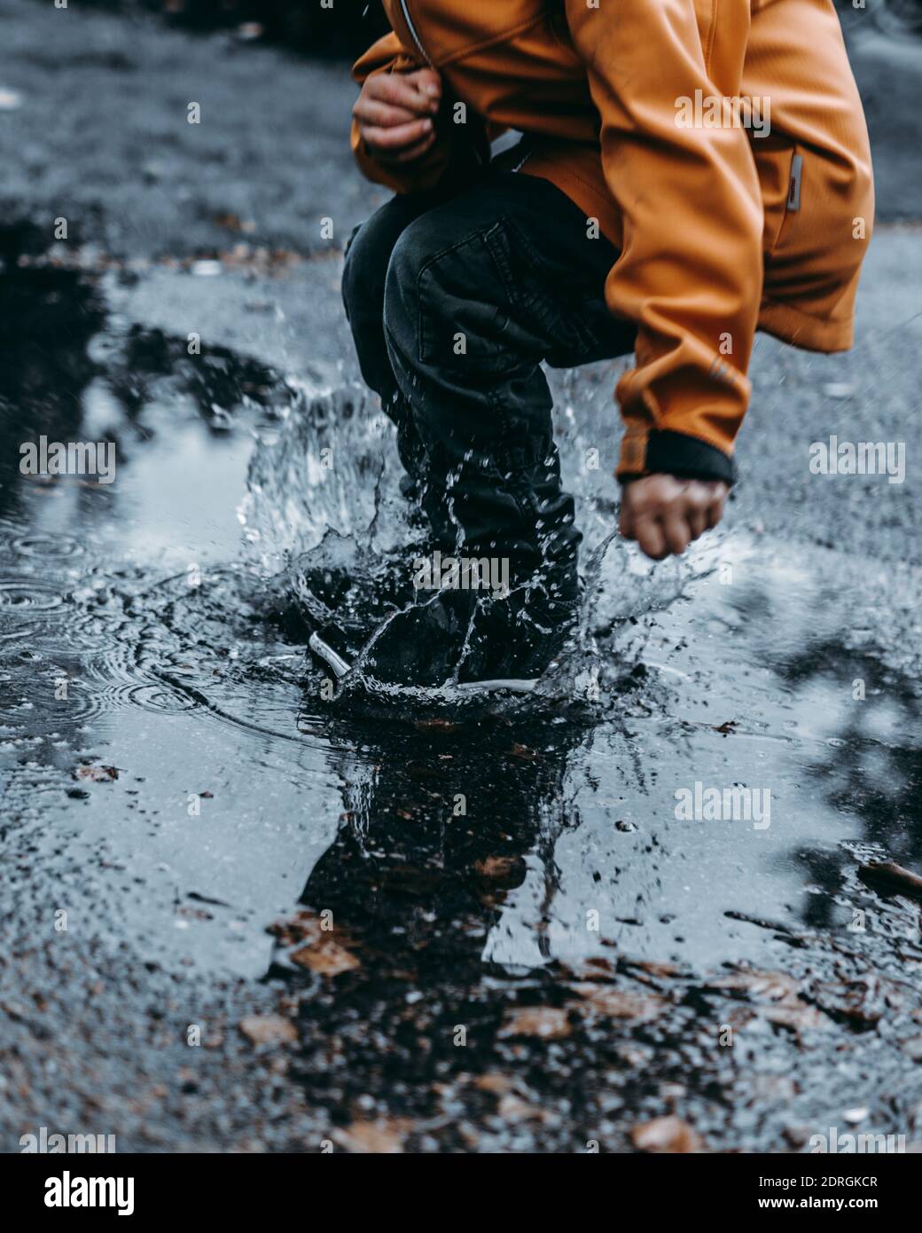 Low Section Of Man Jumping On Puddle Stock Photo - Alamy