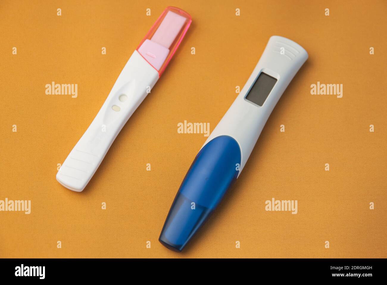 Two pregnancy tests, digital and analog, lie on a yellow background ...