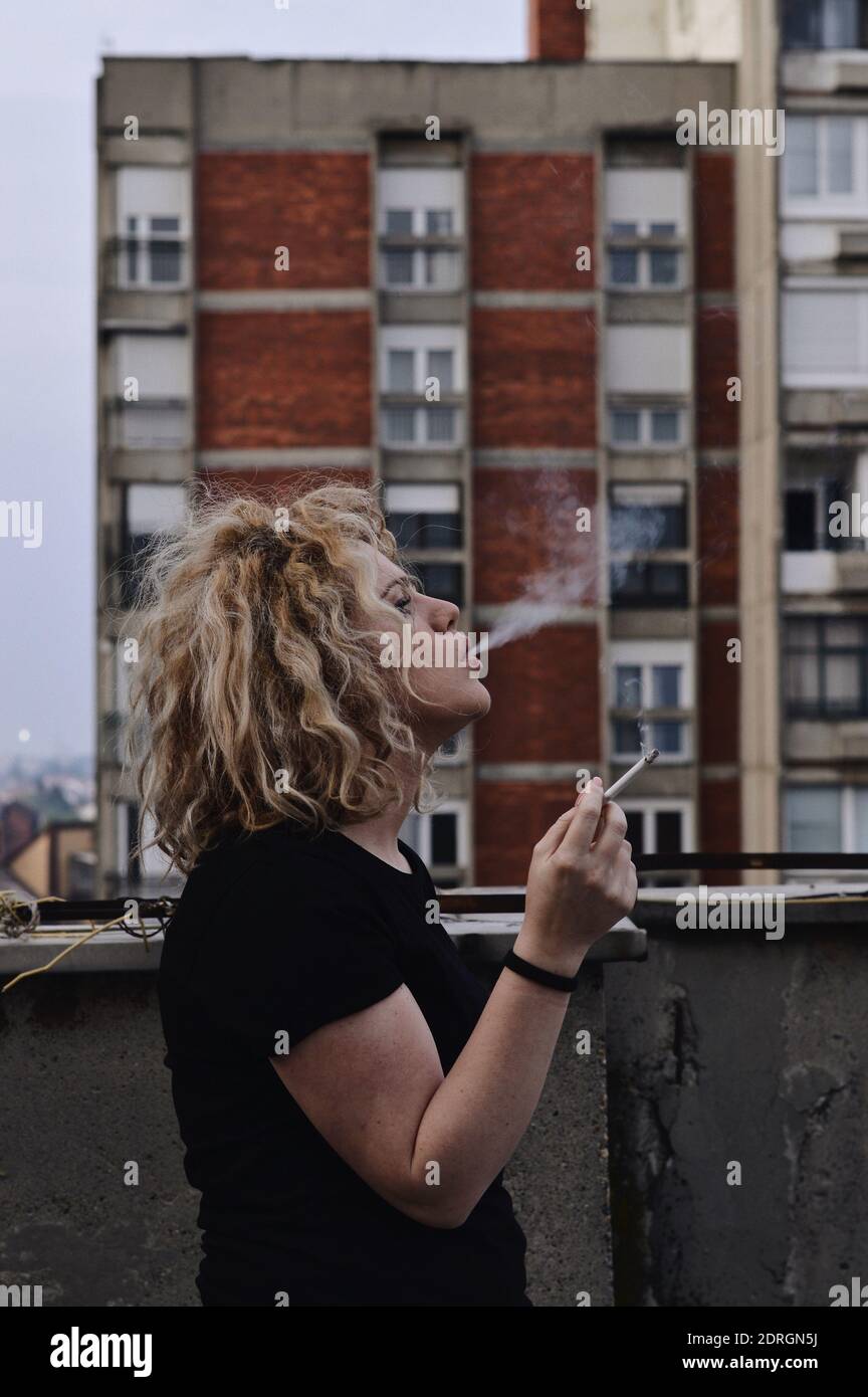 Side View Of Young Woman Smoking Cigarette In Building Terrace Stock ...