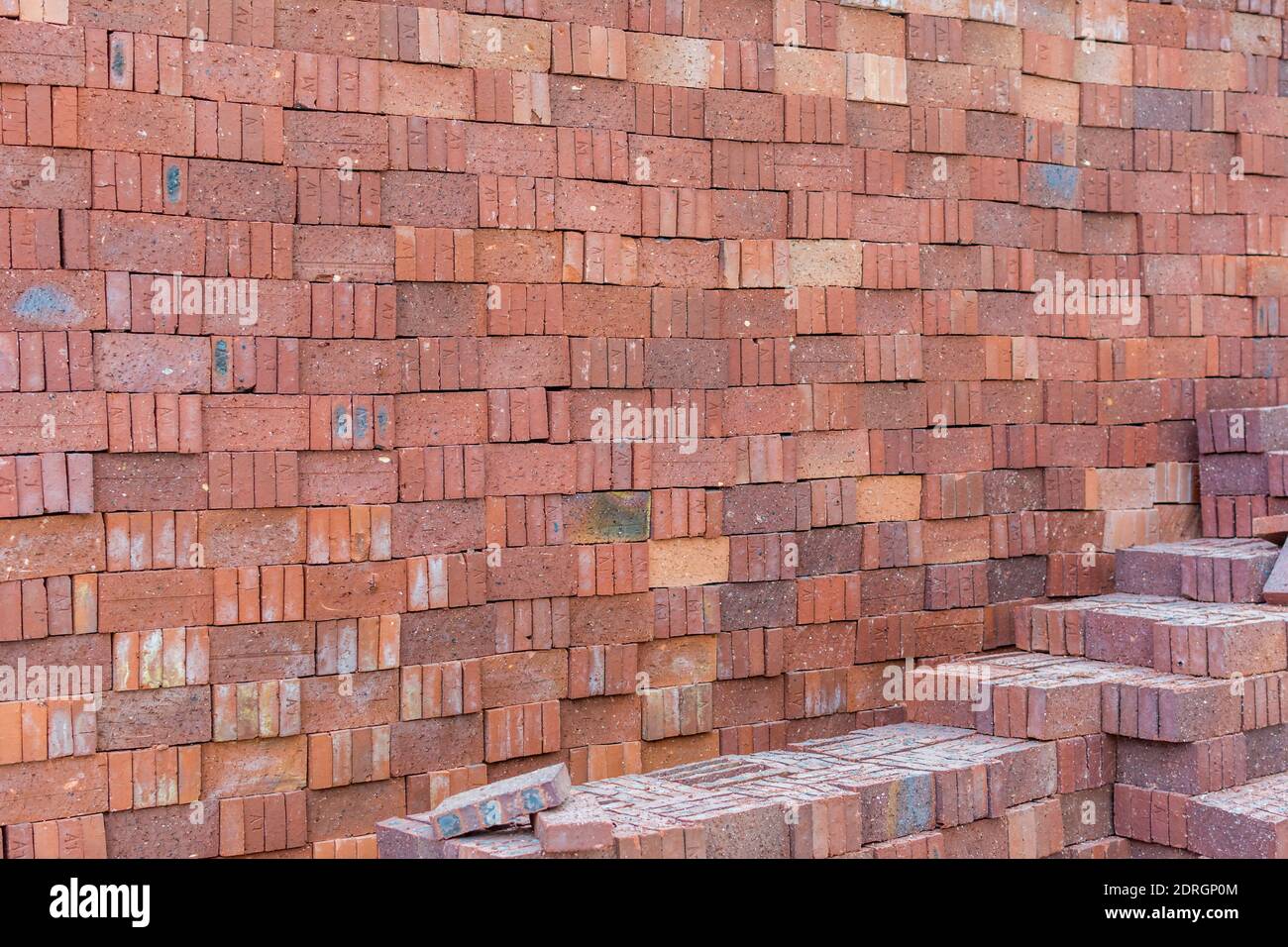 Red bricks piled up into wall ready for construction Stock Photo - Alamy