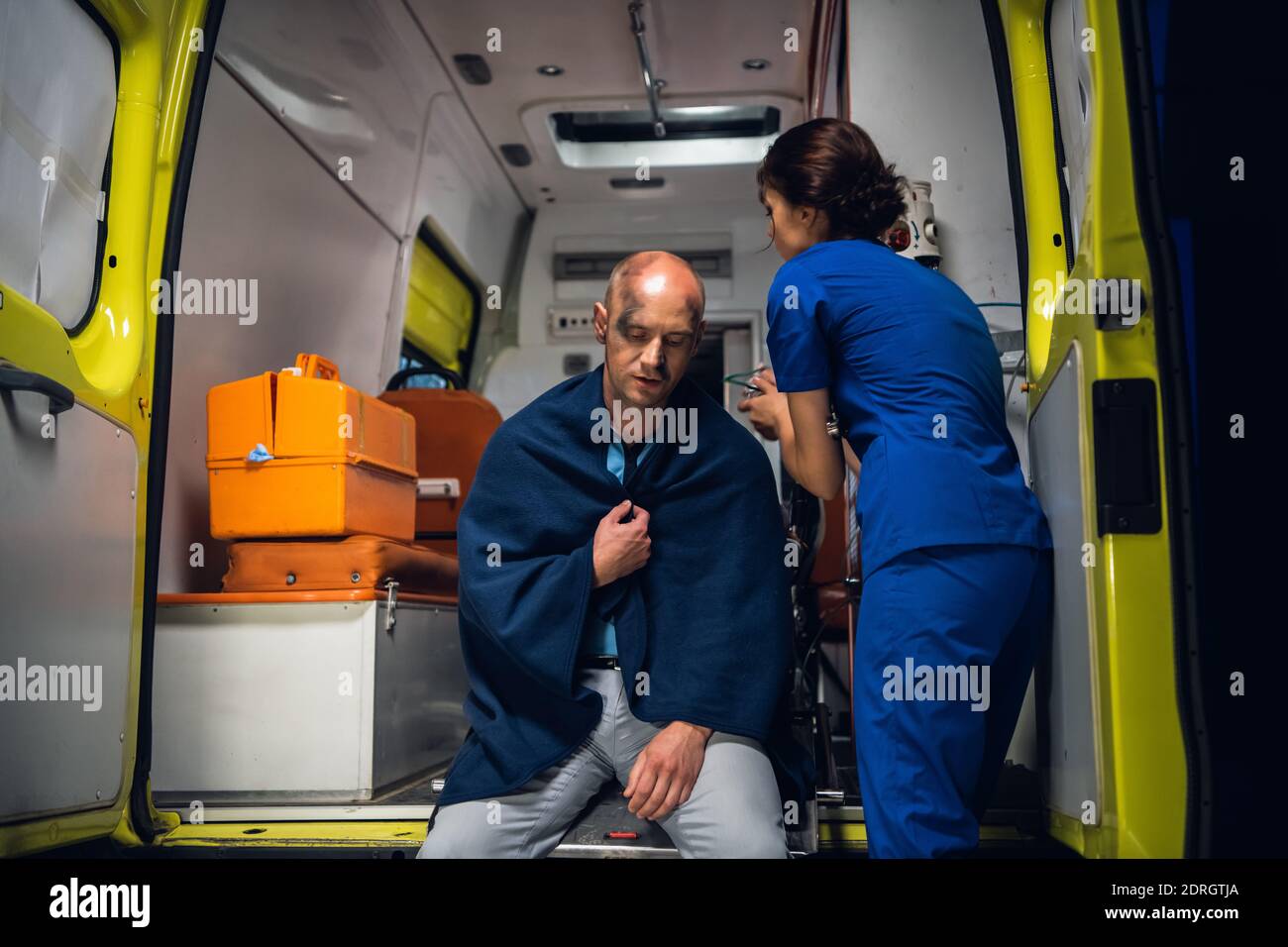 A female paramedic providing first aid to an injured man resqued from ...