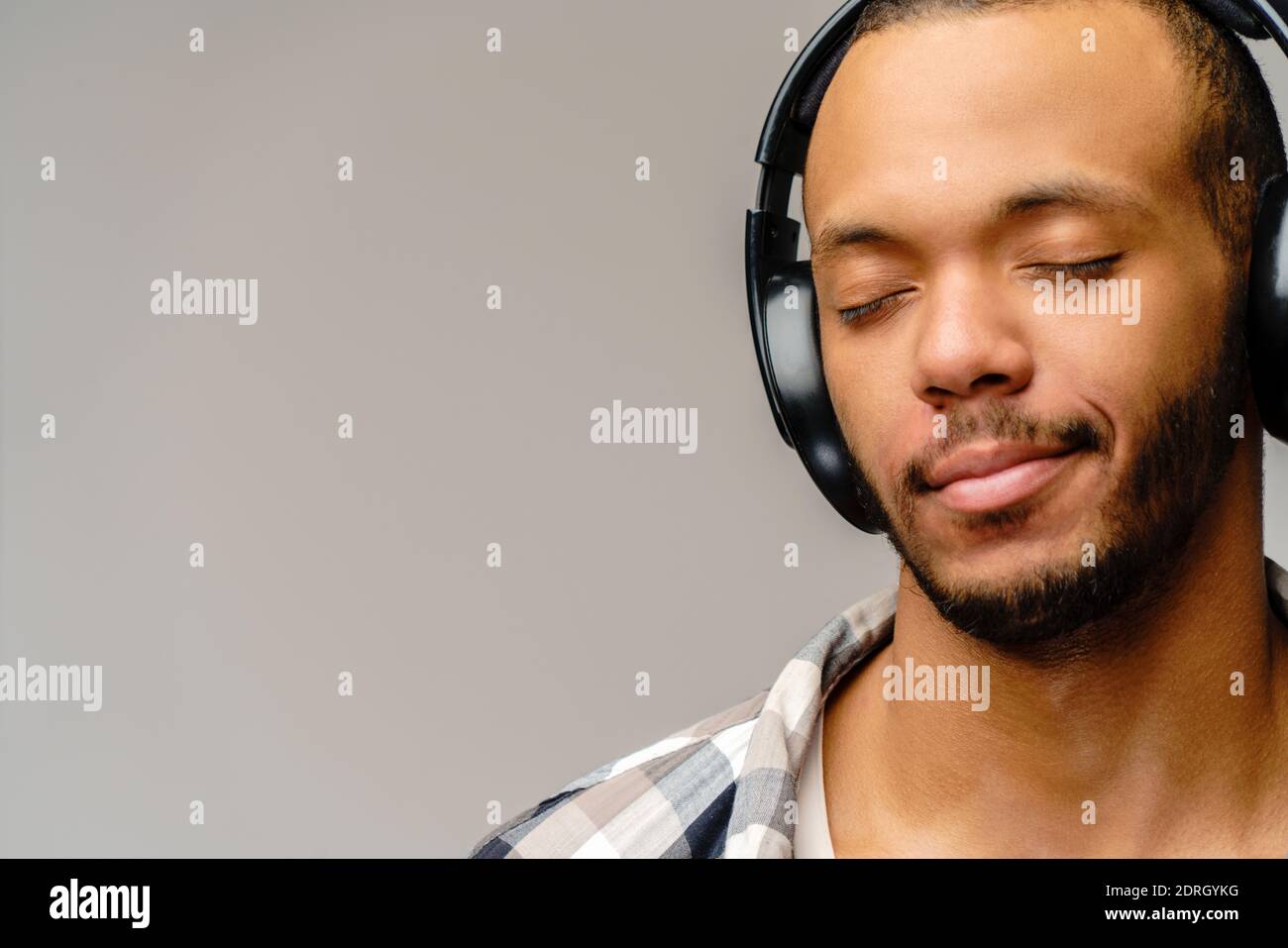Young African American Man Listening To Music On Large Earphones