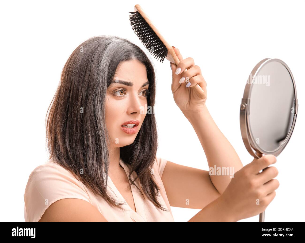 Stressed woman with graying hair looking in mirror on white background ...