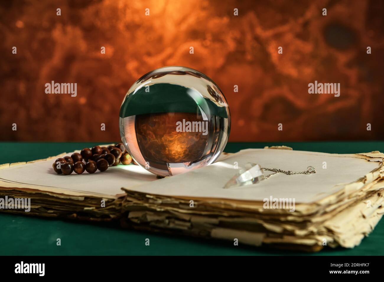 Spell book, crystal ball, pendulum and beads on table Stock Photo - Alamy