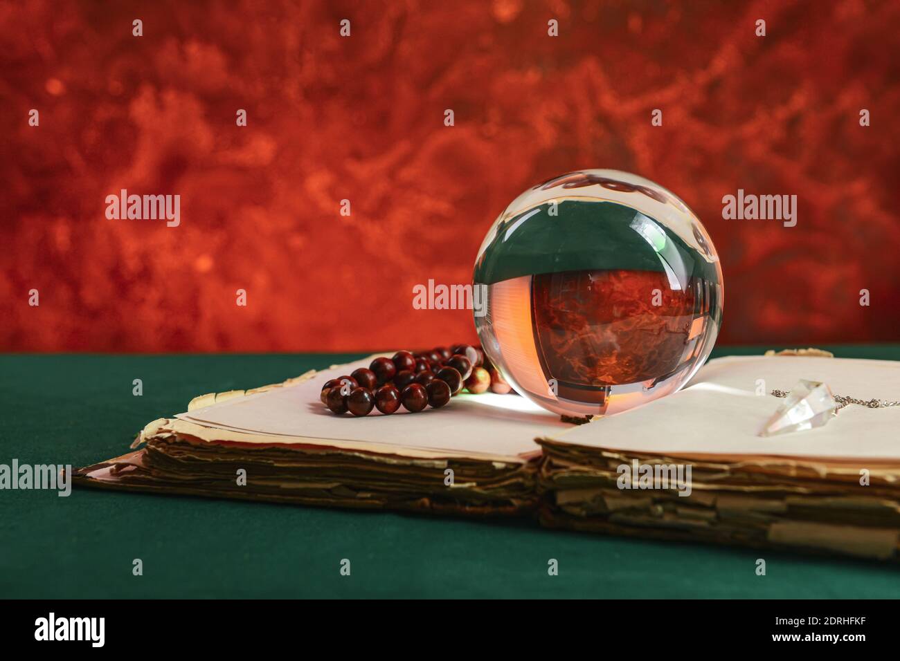 Spell book, crystal ball, pendulum and beads on table Stock Photo - Alamy