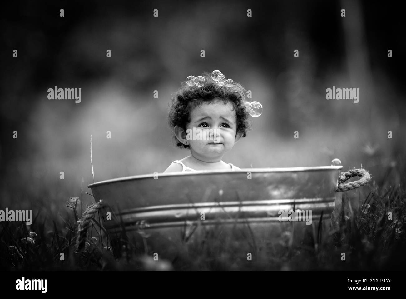 Baby Girl Sitting In Bucket On Field Stock Photo - Alamy