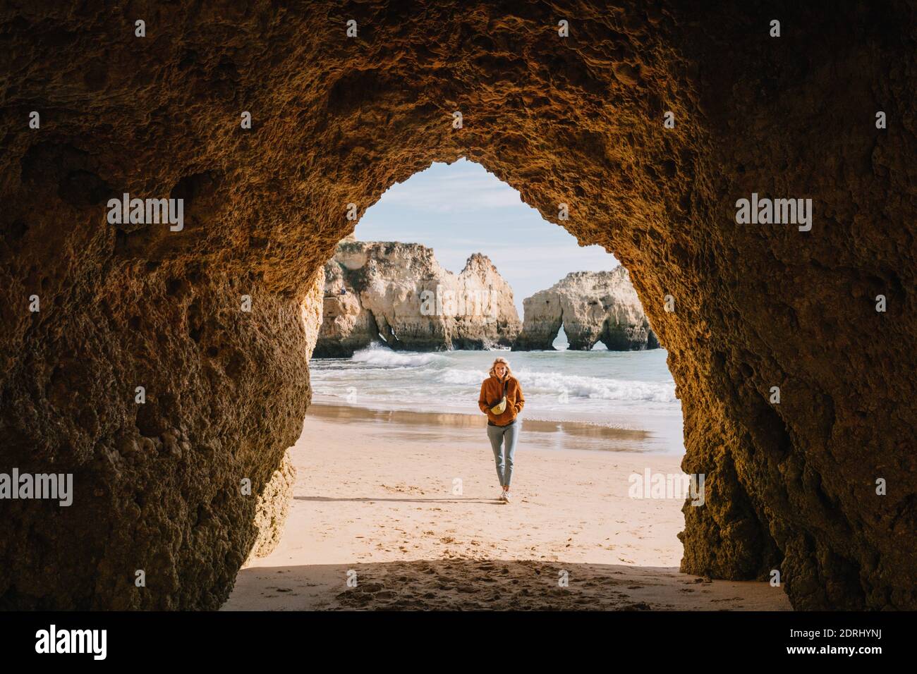 Woman Walking At Beach Seen Through Cave Stock Photo - Alamy