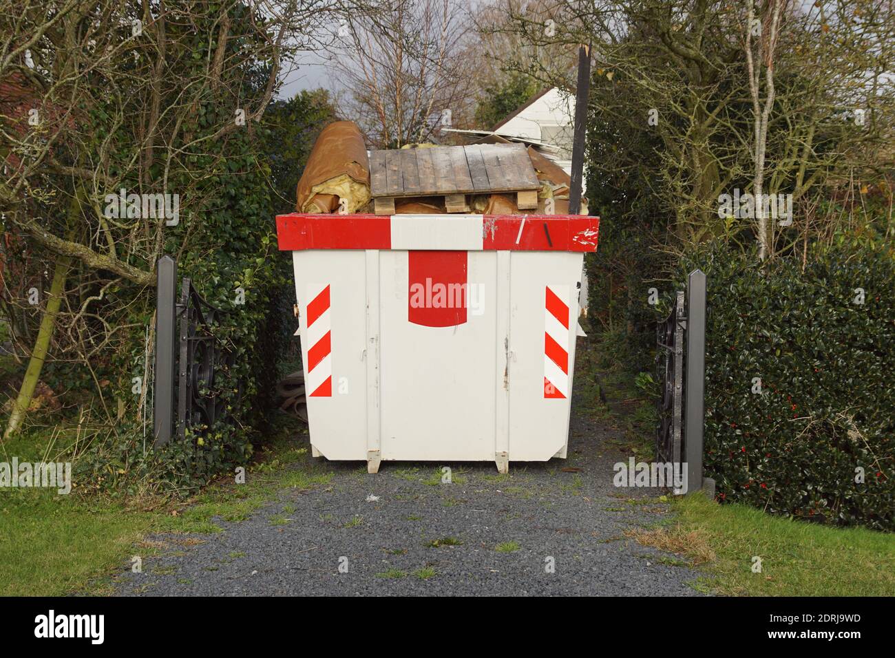 Industrial white red rubbish skip on driveway. Selective focus on full ...