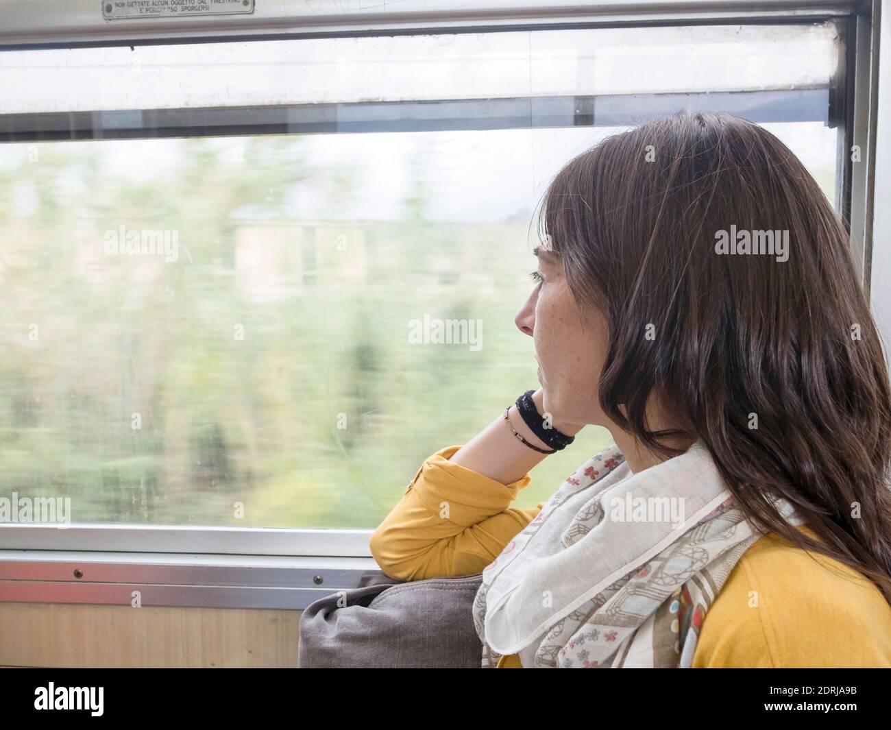Young woman traveler looking through window inside of suburban train ...