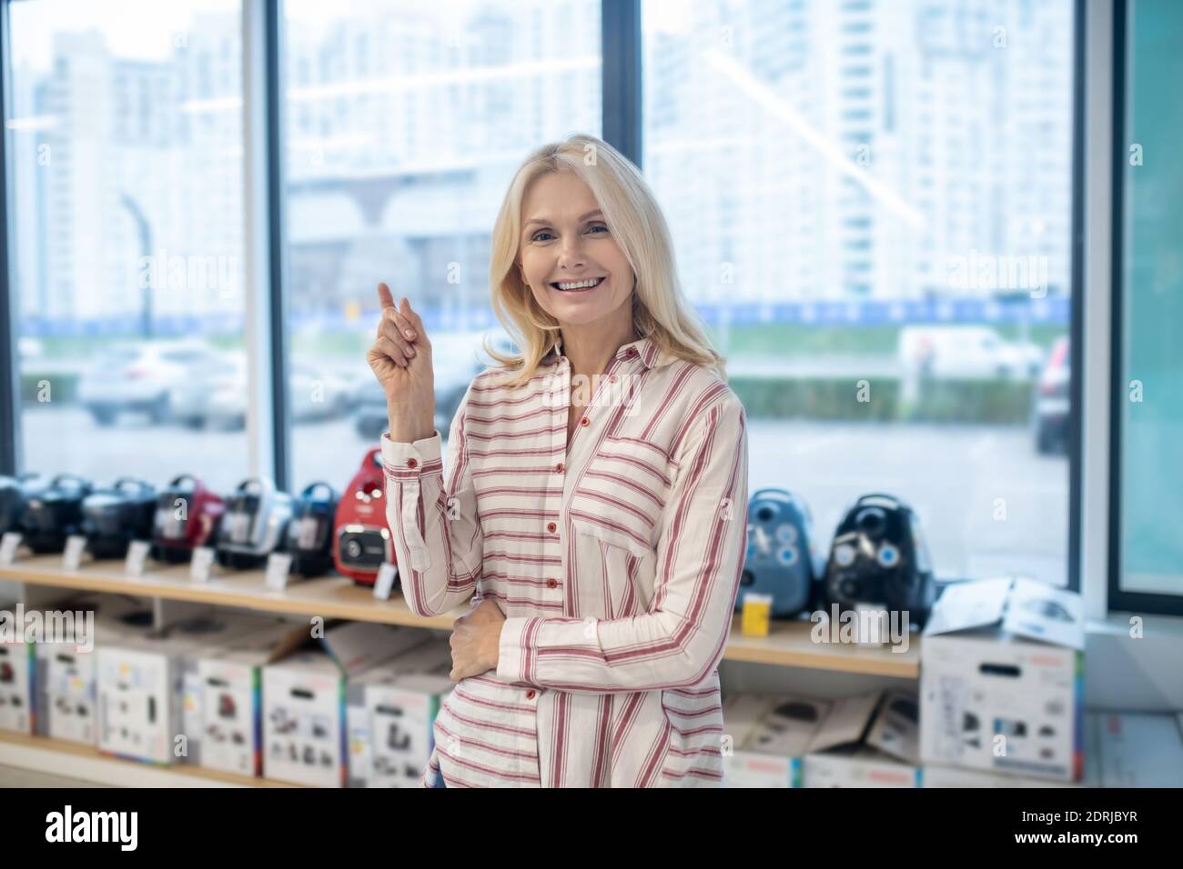 Blonde female customer standing in a consumer goods showroom and ...