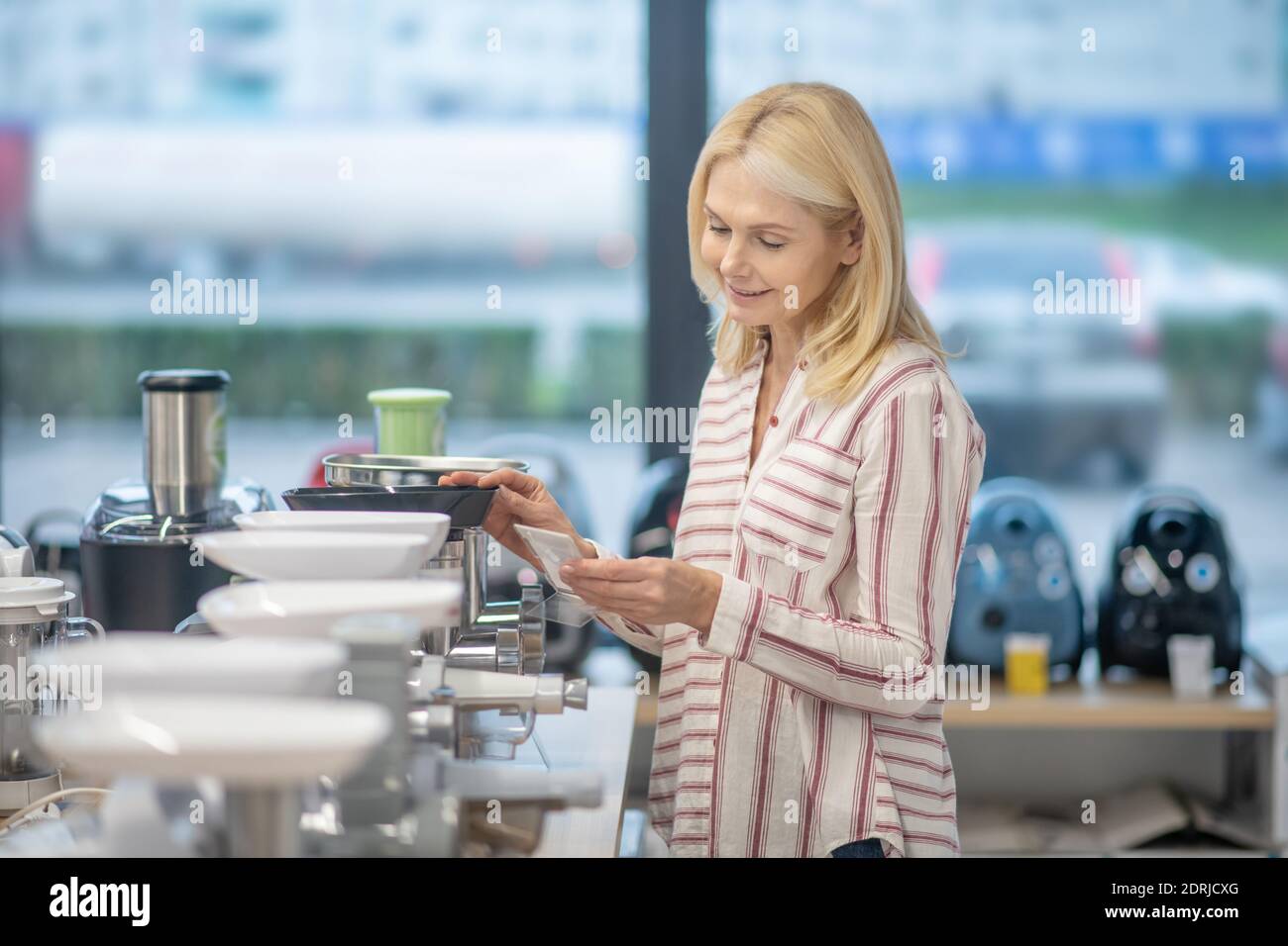Blonde female customer standing in a consumer goods showroom and ...