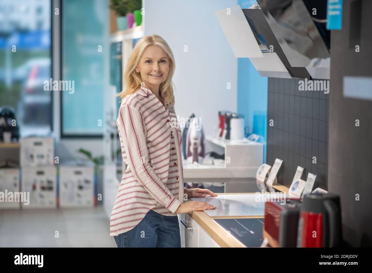 Blonde female customer standing in a consumer goods showroom and ...