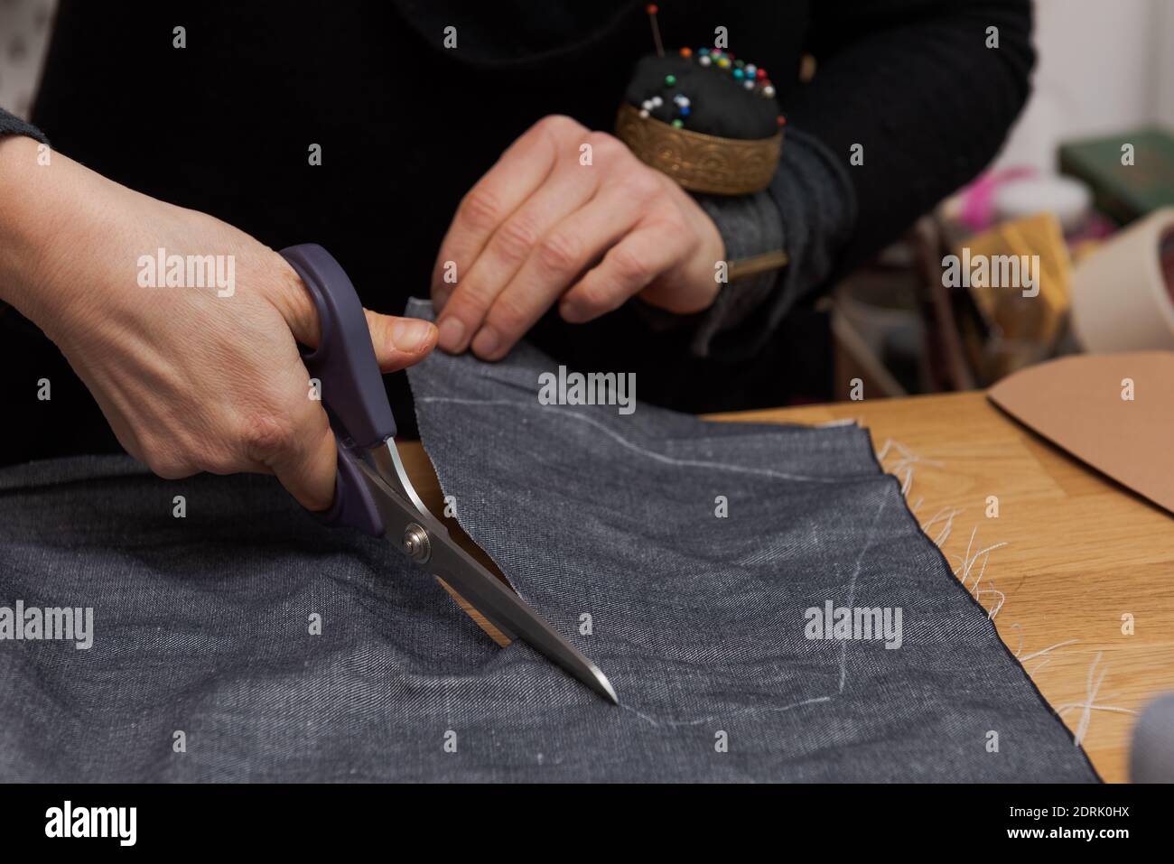 Human hands cutting out the template of fabric with dressmaker shear ...