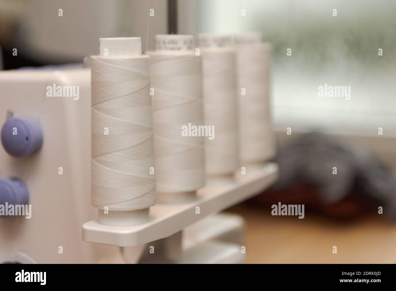 Detail of four thread spools with white thread on overlock sewing ...