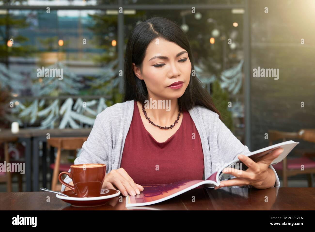 Woman reading magazine in coffeeshop Stock Photo - Alamy