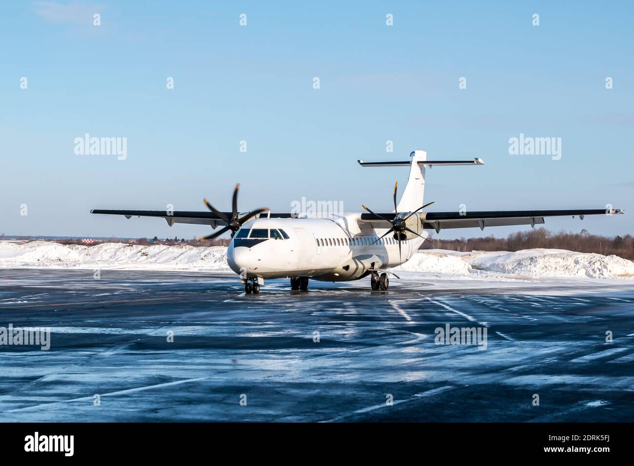 White passenger turboprop airplane on the airport apron in cold winter ...