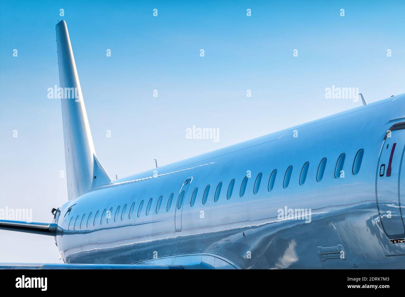 Close-up of the fuselage of a white passenger airplane on a clear sunny ...