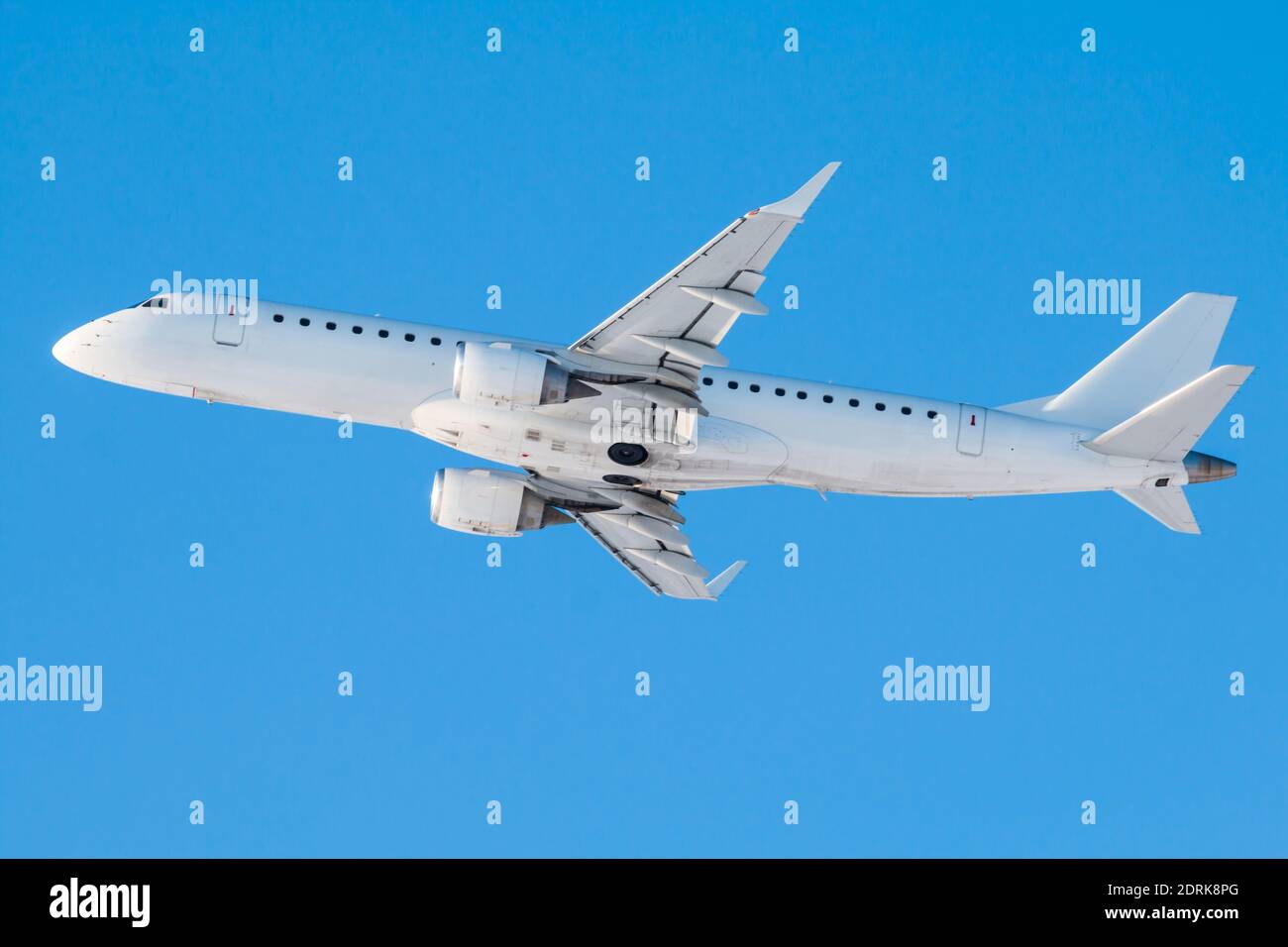 Modern white passenger jet plane flies in the air on a clear sunny day ...