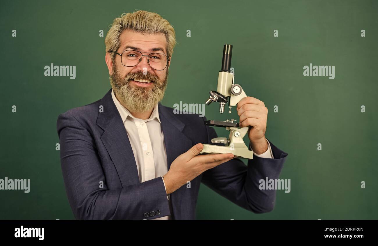 Fascinating research. Teacher with microscope. Man hipster classroom ...