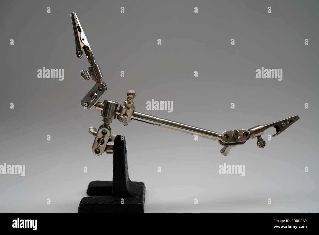 A closeup of a metal helpful third hand with crocodile clamps in front ...