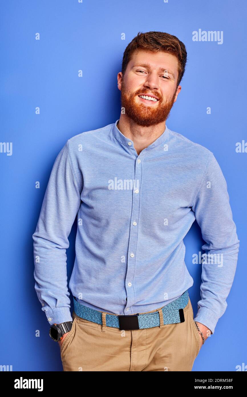 intelligent man in shirt posing at camera isolated over blue background ...