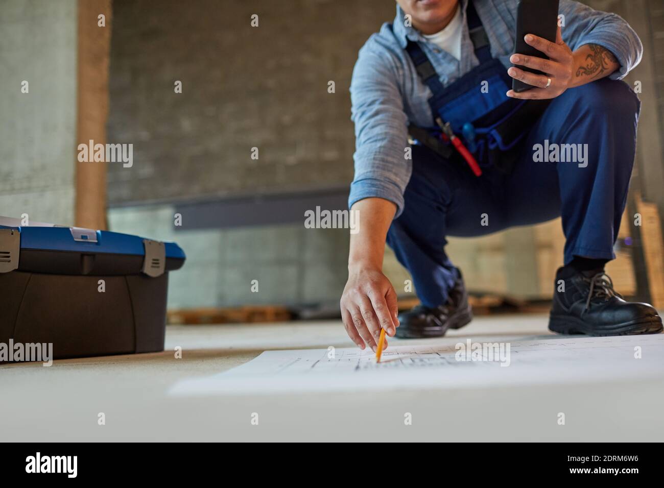 Close up of female construction worker pointing at blueprints while ...