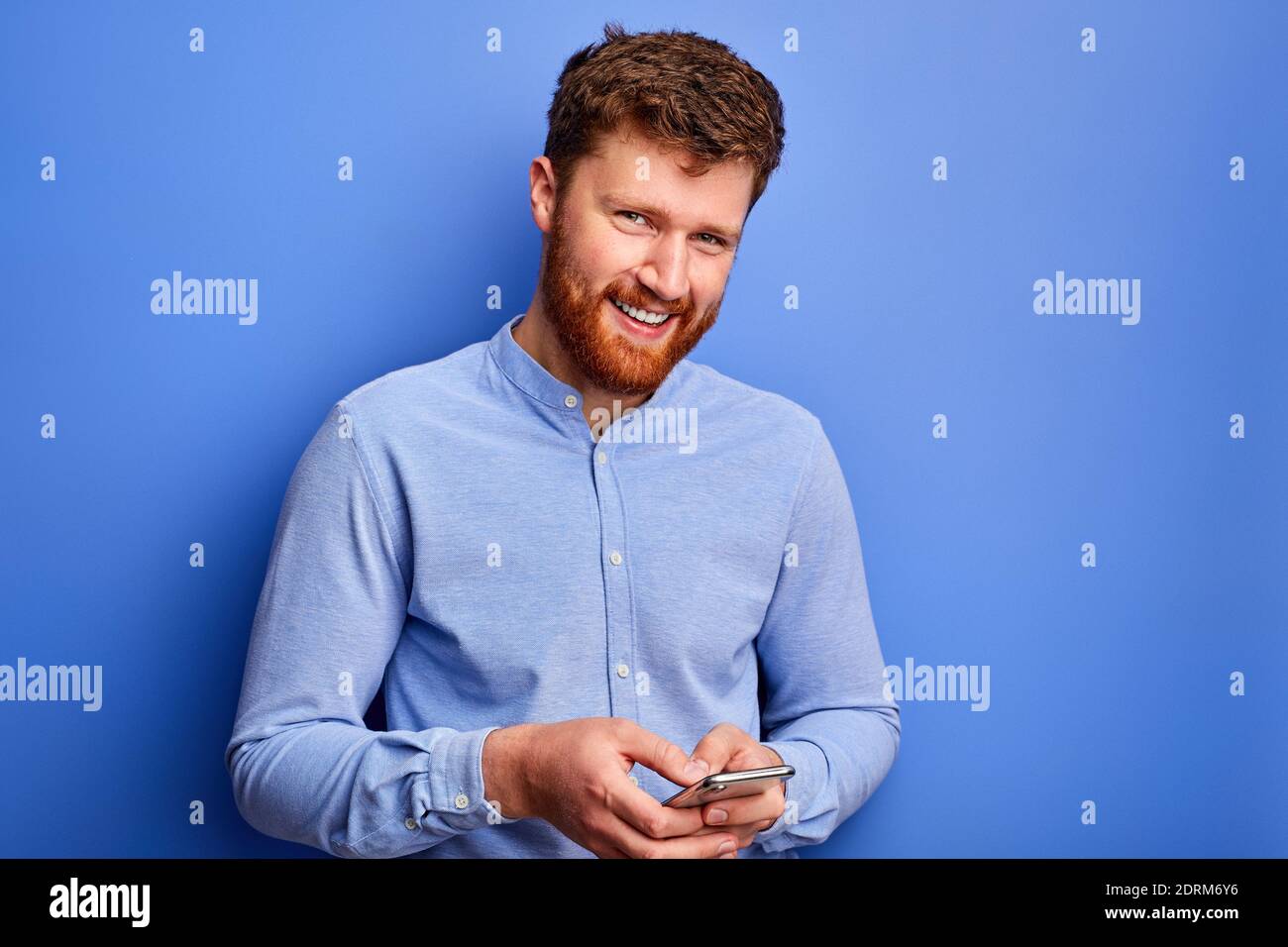 open-minded male is chatting with friend on smartphone, typing message ...