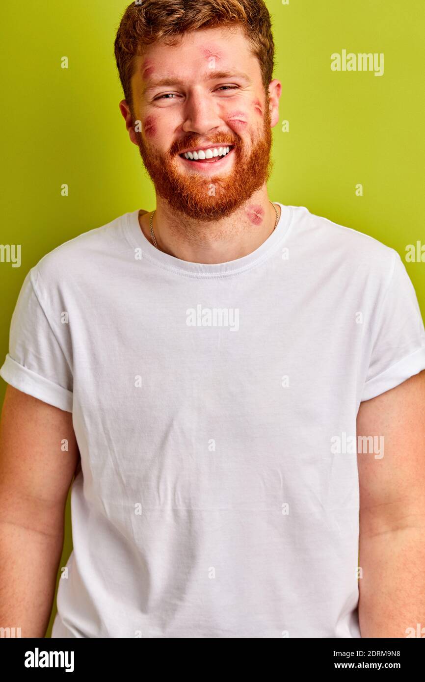 happy male with red kisses marks on cheek, enjoy. caucasian guy in ...