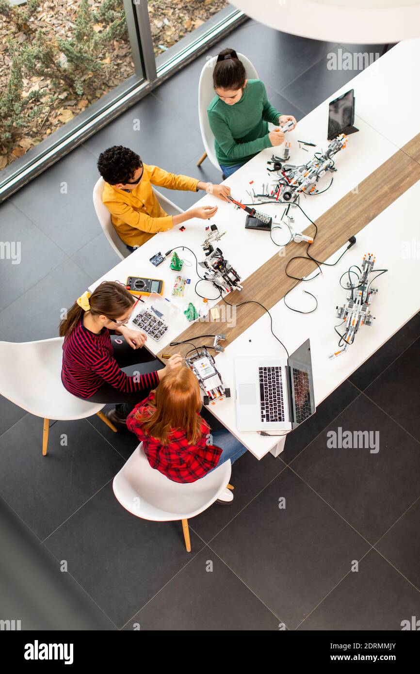Group of happy kids programming electric toys and robots at robotics ...