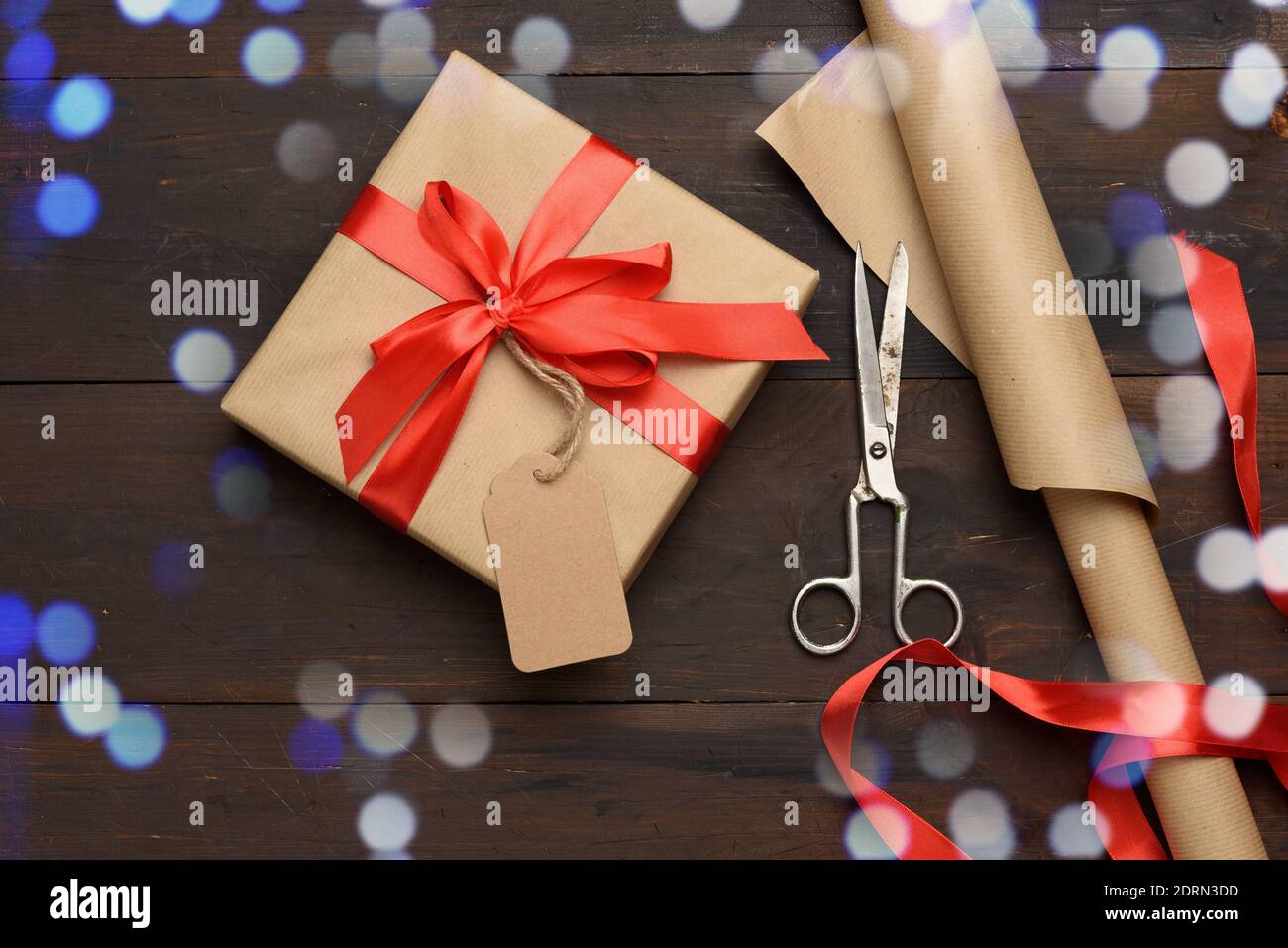 roll of brown kraft packaging paper, red silk ribbon, scissors and a ...