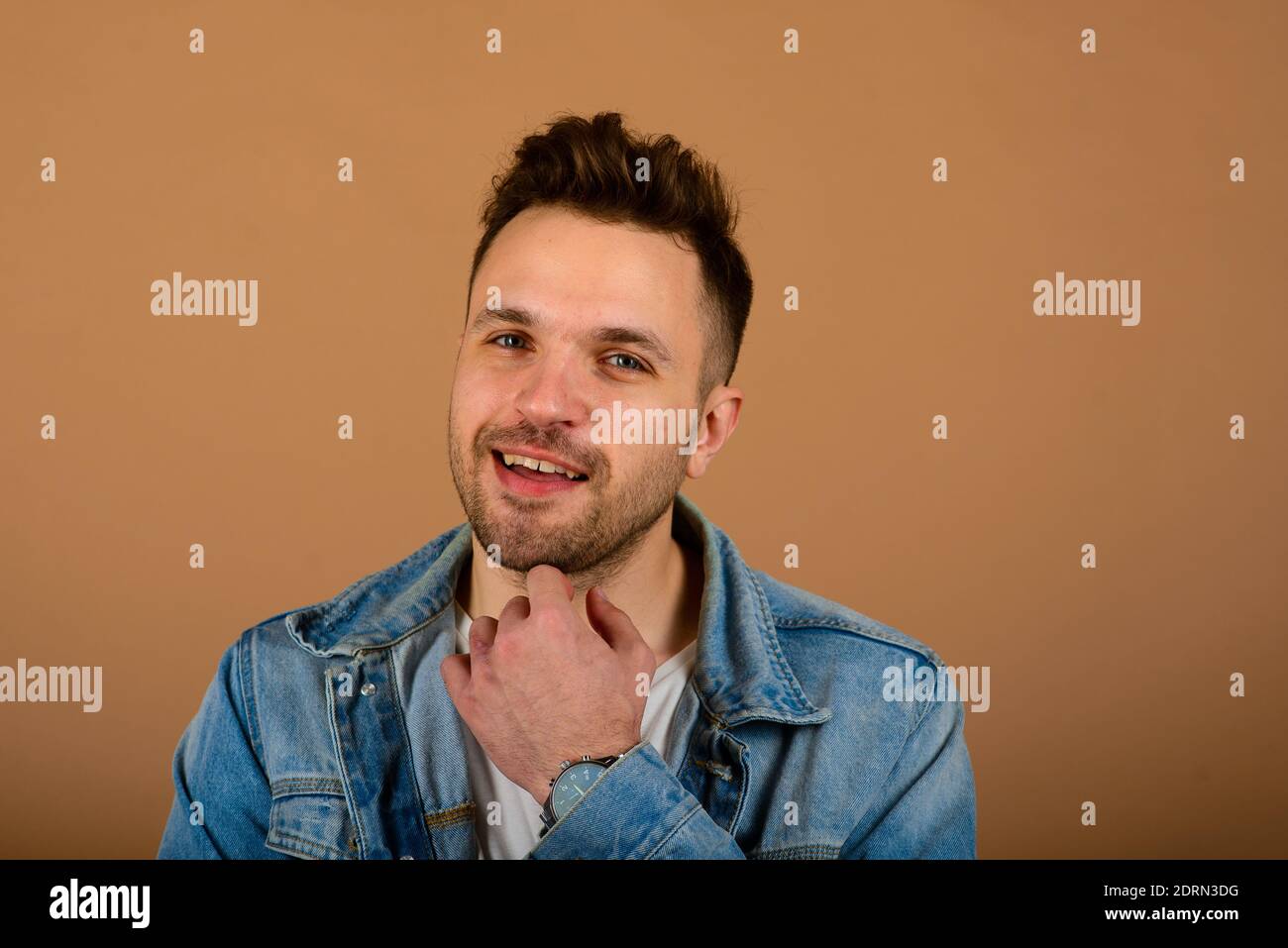 Handsome man standing and smiling isolated on the light brown studio ...